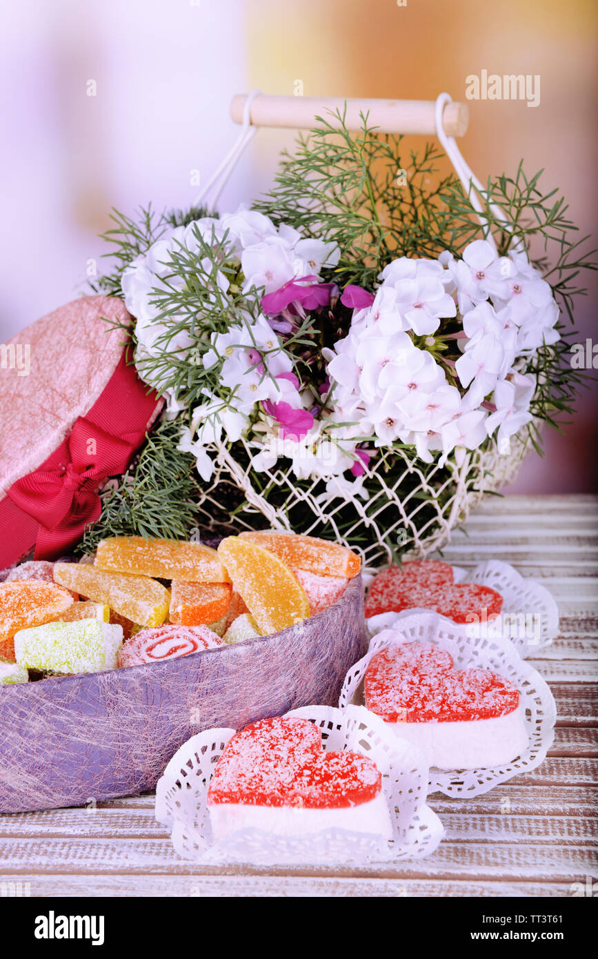 Present box with sweets and flowers on table on bright background Stock ...
