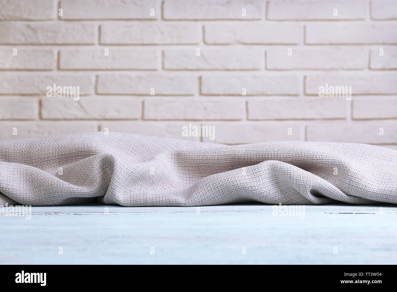 Wooden table with cloth on wall background Stock Photo - Alamy