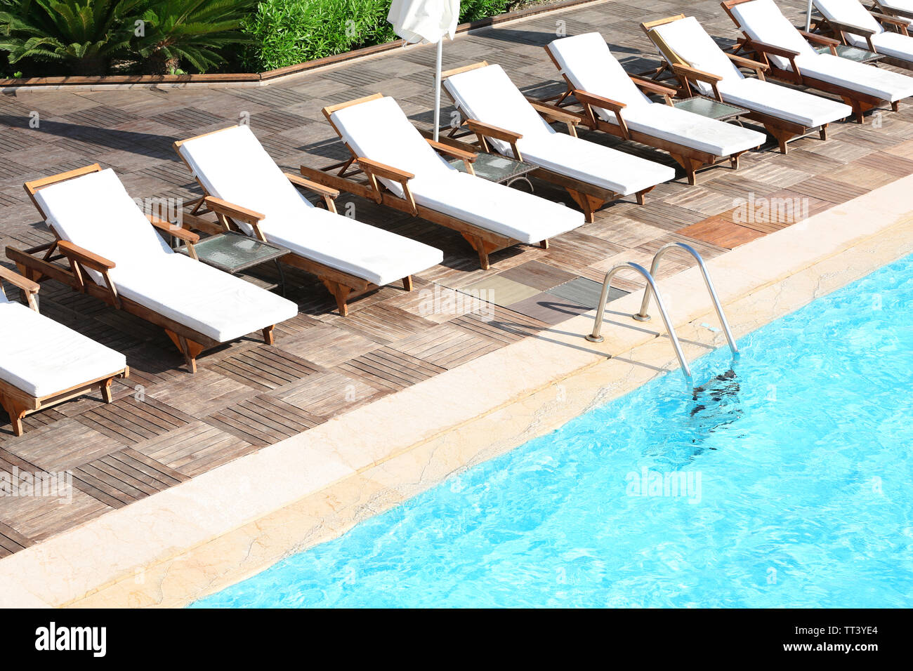 Lounge sunbeds near swimming pool Stock Photo - Alamy