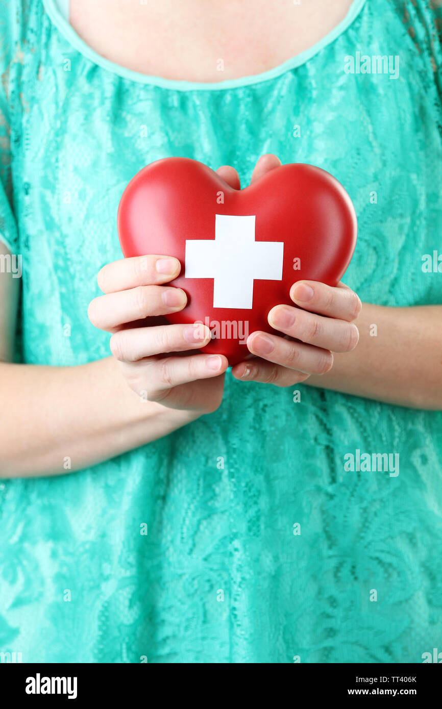 Red heart with cross sign in female hand, close-up Stock Photo - Alamy
