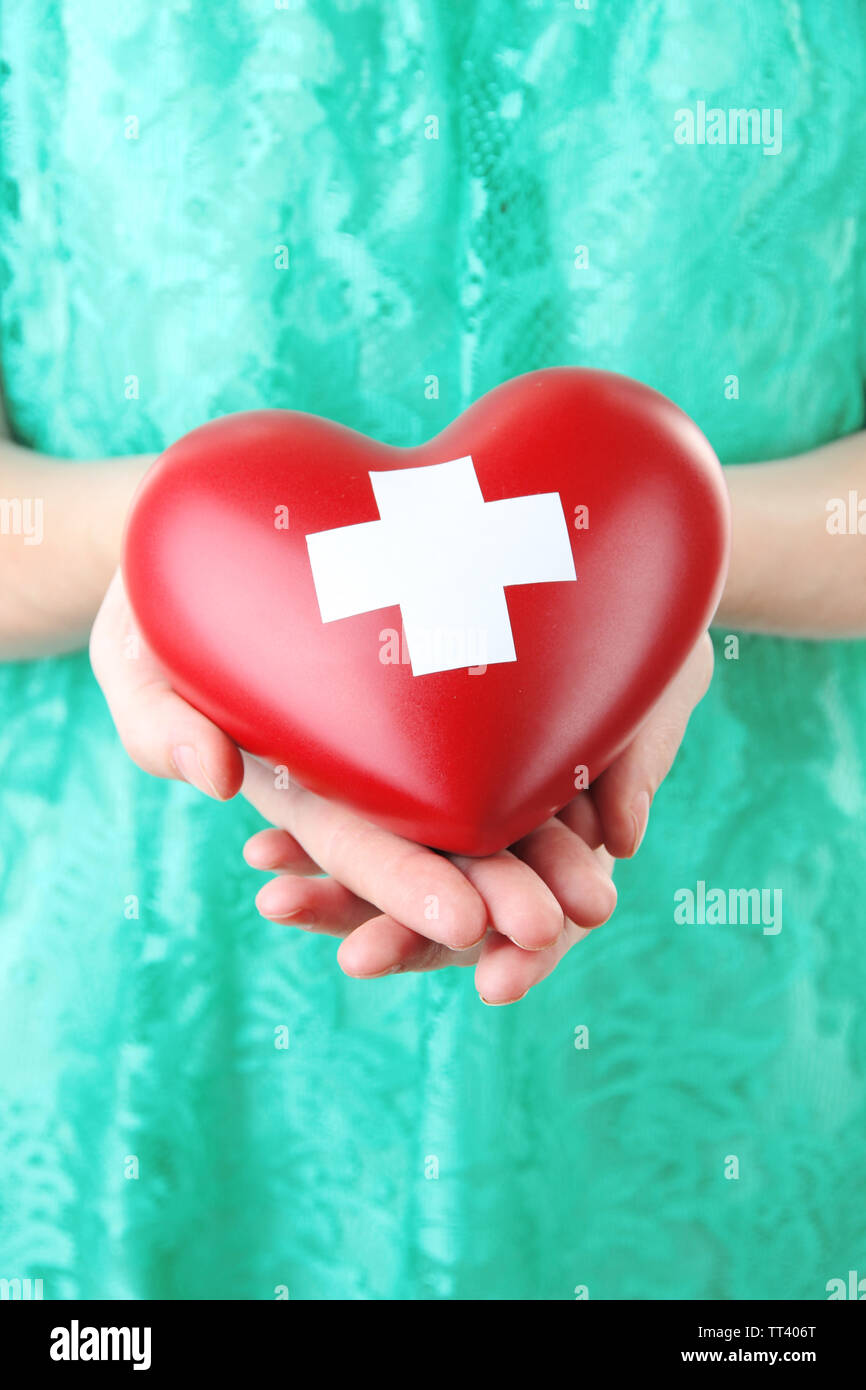 Red heart with cross sign in female hand, close-up Stock Photo - Alamy