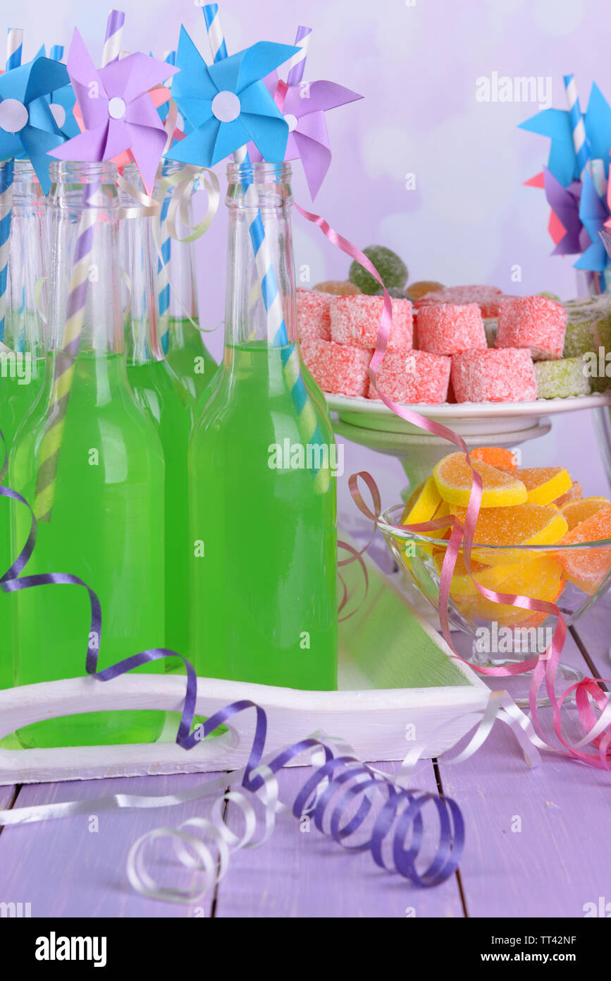 Bottles with drink and sweets on table on bright background Stock Photo ...