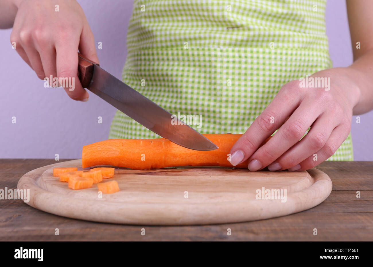 Woman cutting carrot with knife in kitchen on light background Stock ...
