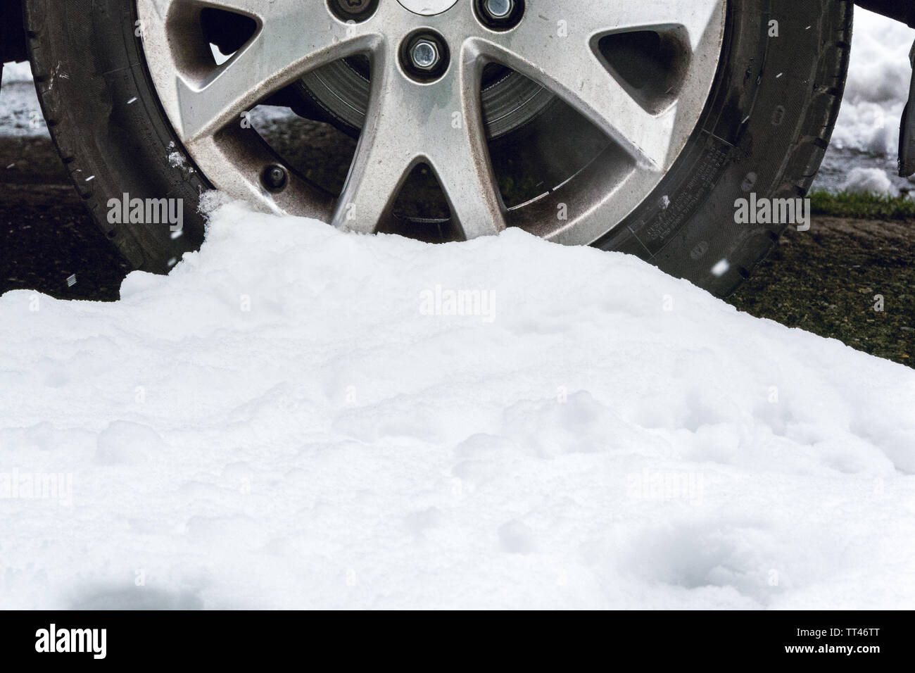 Snow pile and a parked car wheel on snowy morning Stock Photo - Alamy