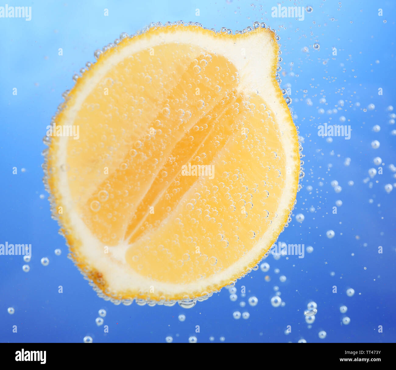 Fresh lemon in water with bubbles on blue background Stock Photo - Alamy