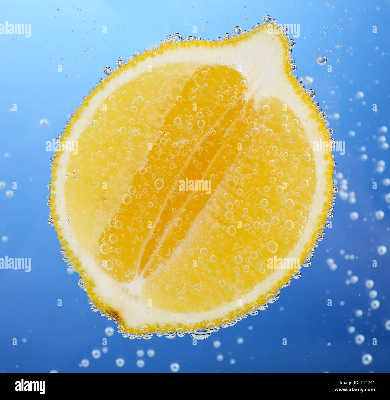 Fresh lemon in water with bubbles on blue background Stock Photo - Alamy