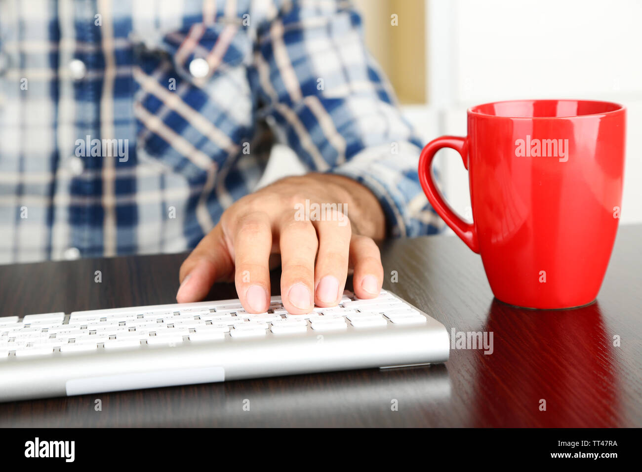 Man working with keyboard on wooden table on folders background closeup ...