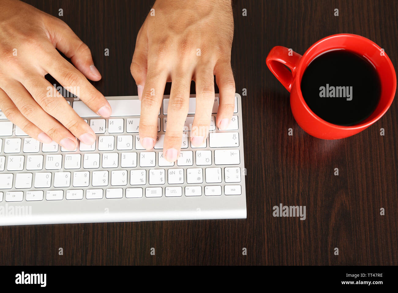 Man working with keyboard on wooden table on folders background closeup ...