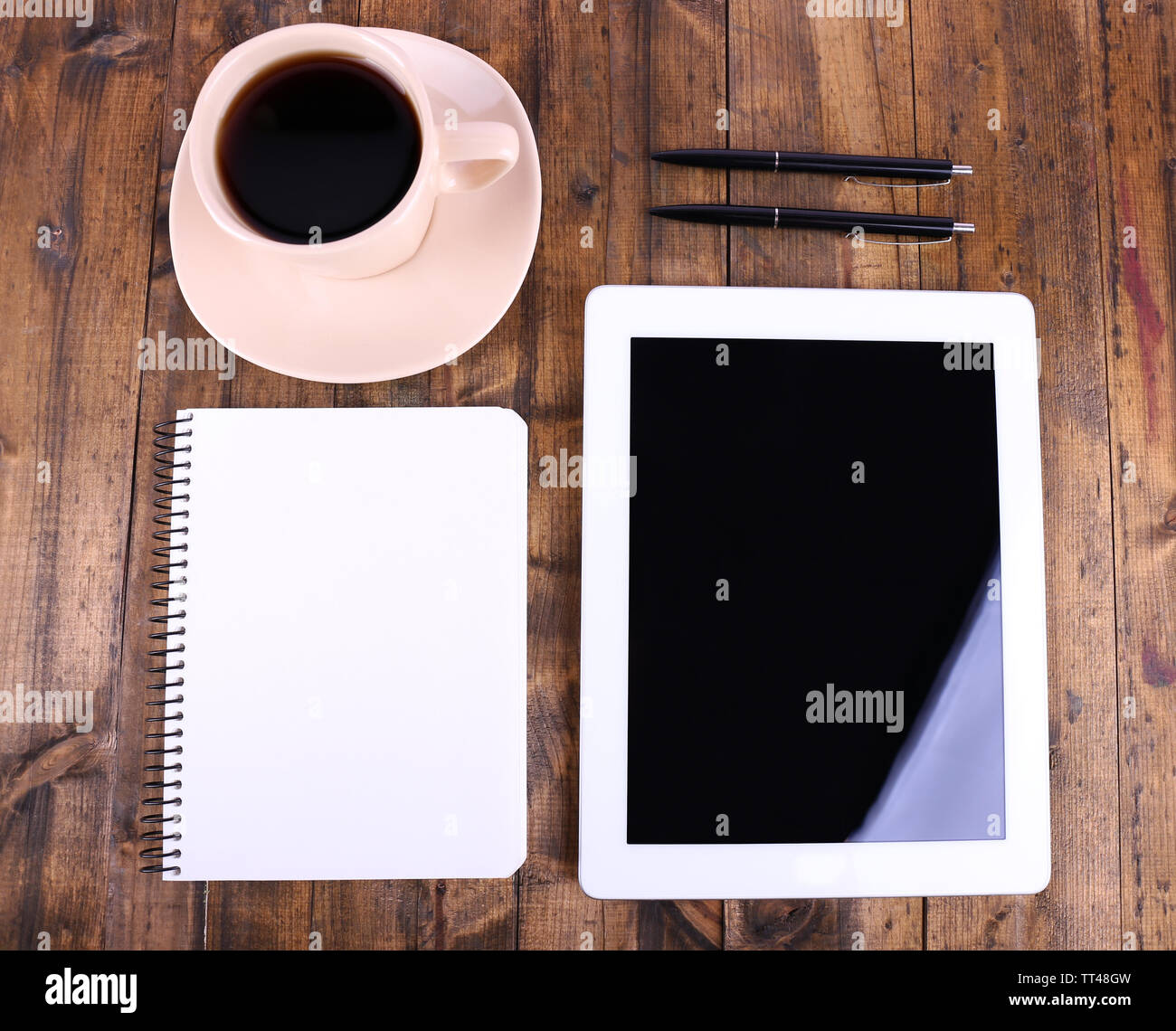 Tablet, cup of coffee, notebook and pens on wooden background Stock ...
