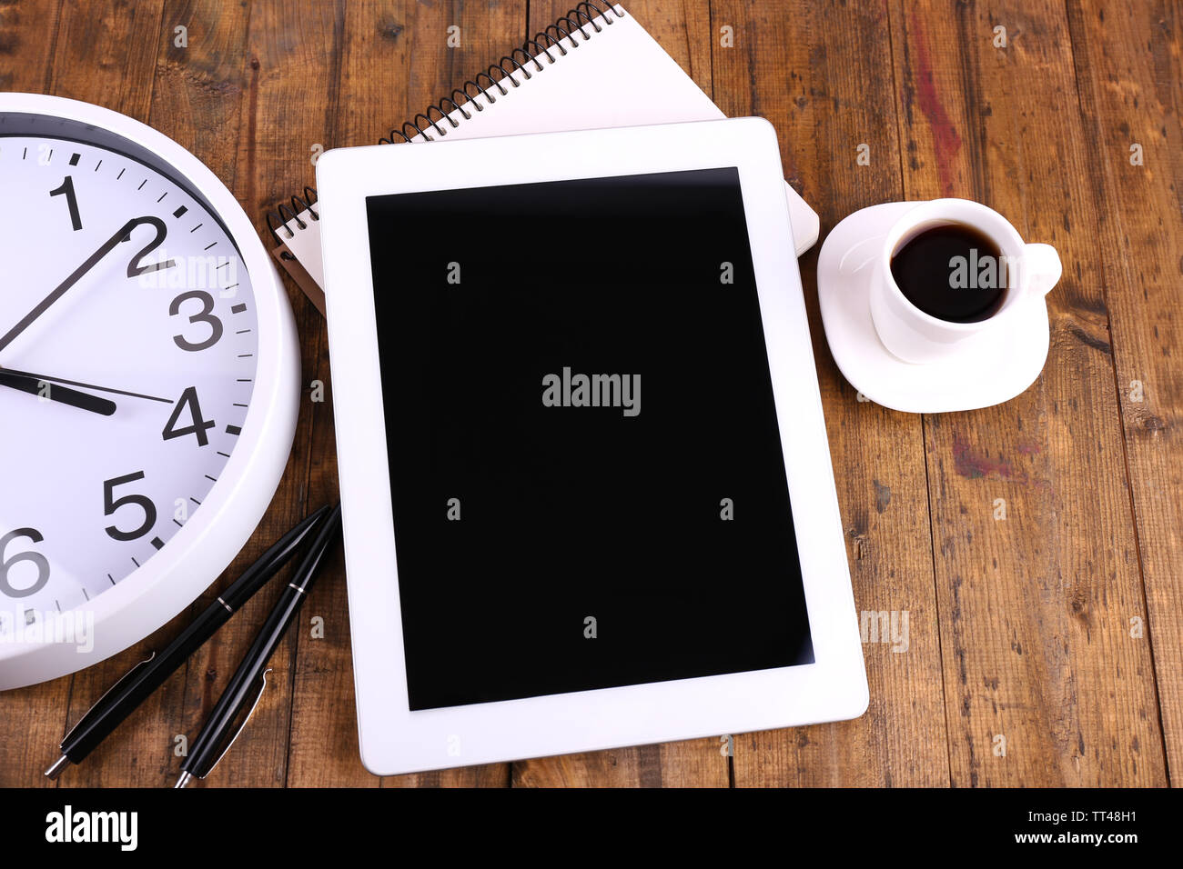 Tablet, cup of coffee, notebook and clock on wooden background Stock ...