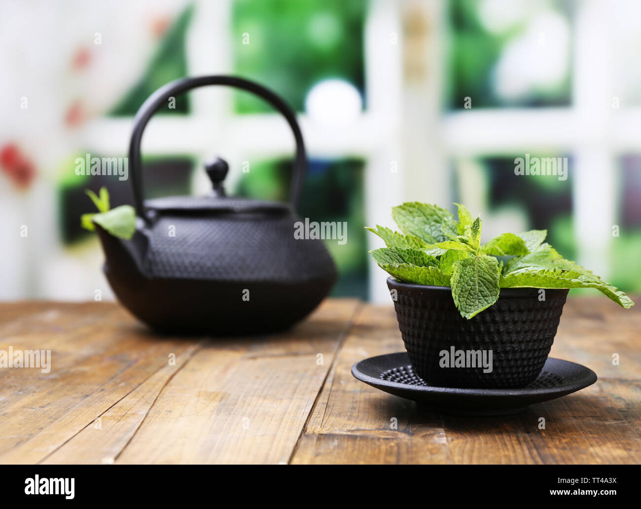 Chinese traditional teapot with fresh mint leaves on wooden table, on ...