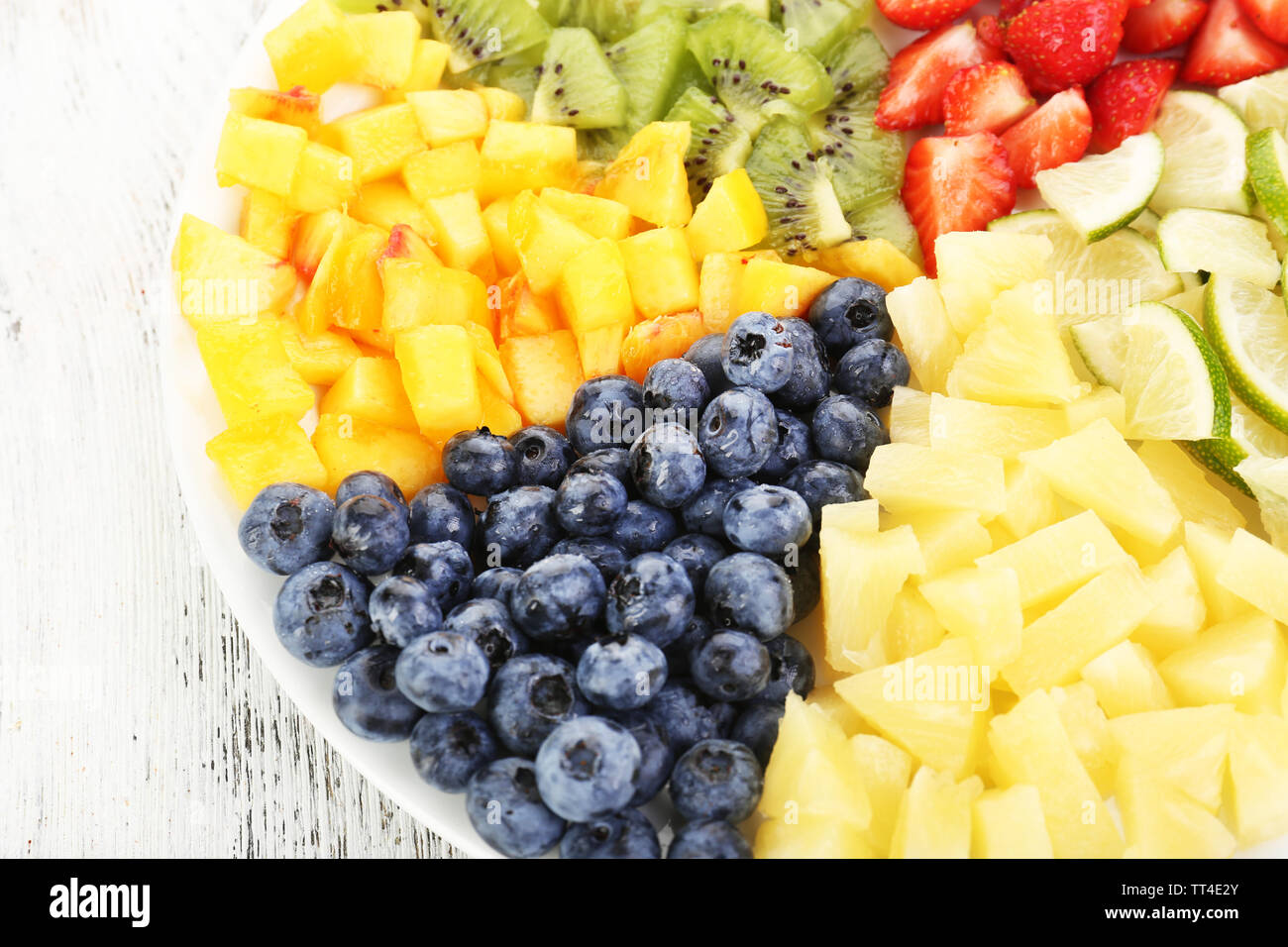 Sliced fruits on plate on wooden table Stock Photo - Alamy