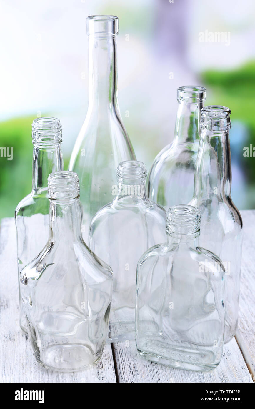 Empty glass bottles on table on bright background Stock Photo - Alamy
