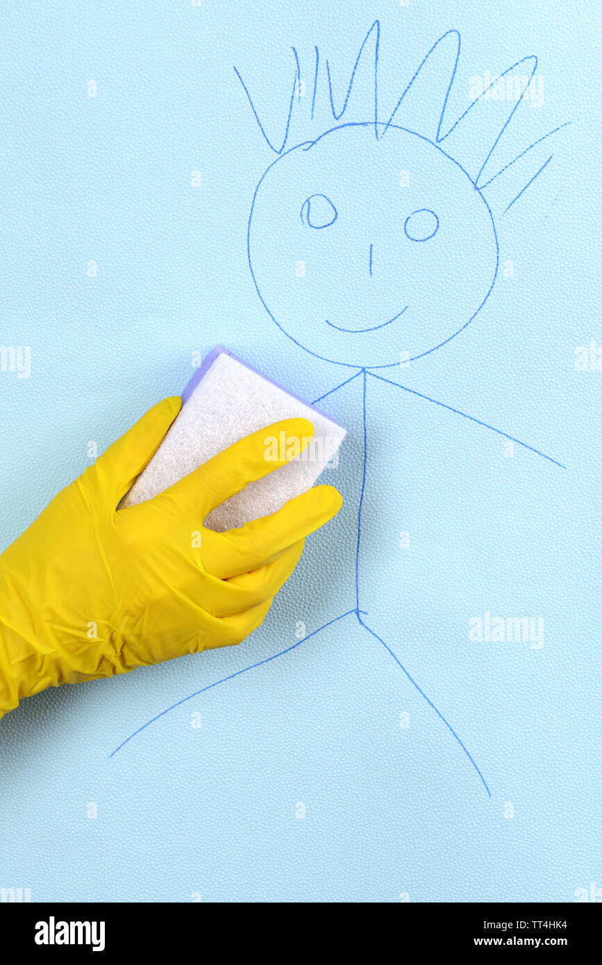 Hand in glove wiping children drawing on wallpaper Stock Photo - Alamy
