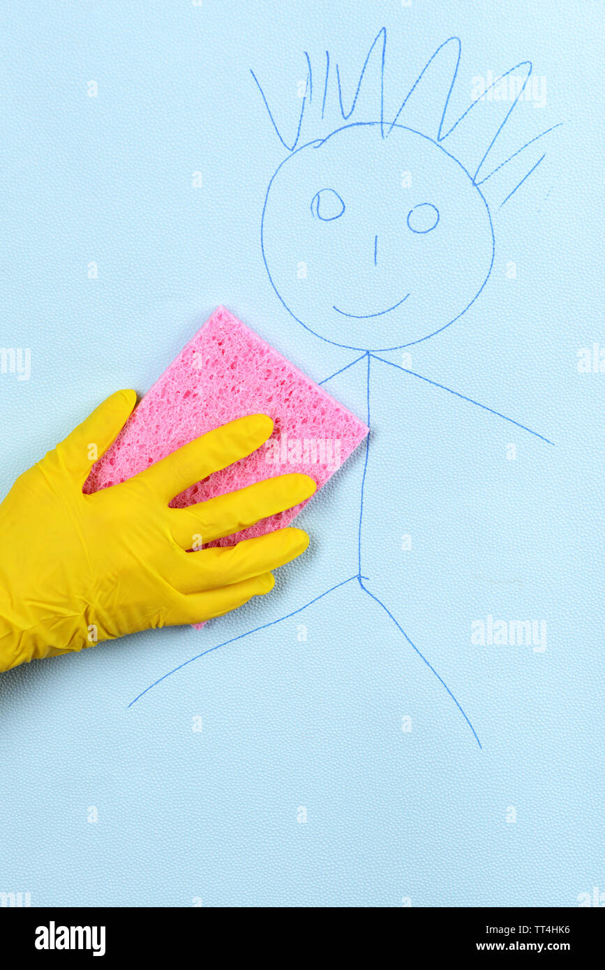 Hand in glove wiping children drawing on wallpaper Stock Photo - Alamy