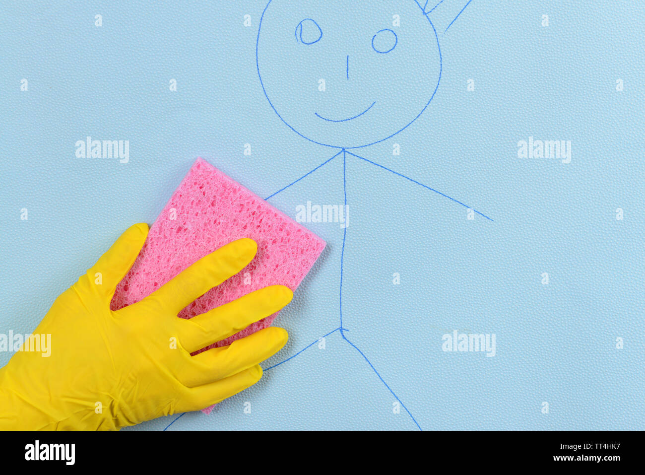 Hand in glove wiping children drawing on wallpaper Stock Photo - Alamy