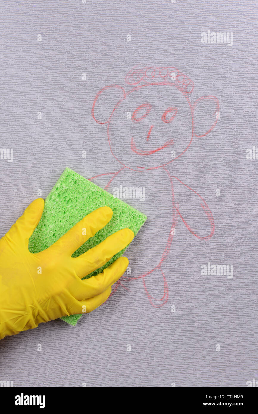 Hand in glove wiping children drawing on wallpaper Stock Photo - Alamy