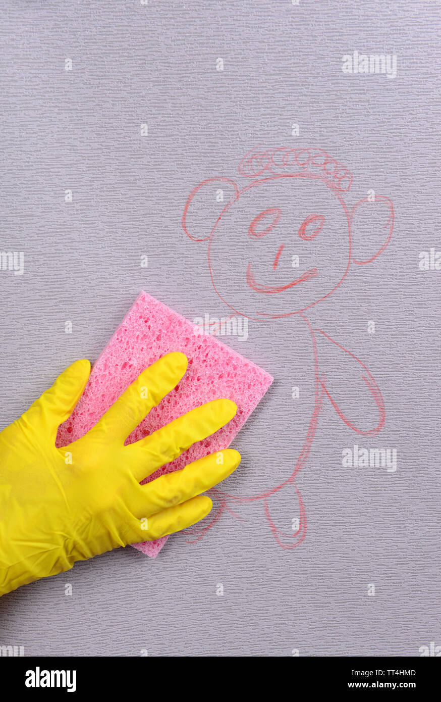 Hand in glove wiping children drawing on wallpaper Stock Photo - Alamy
