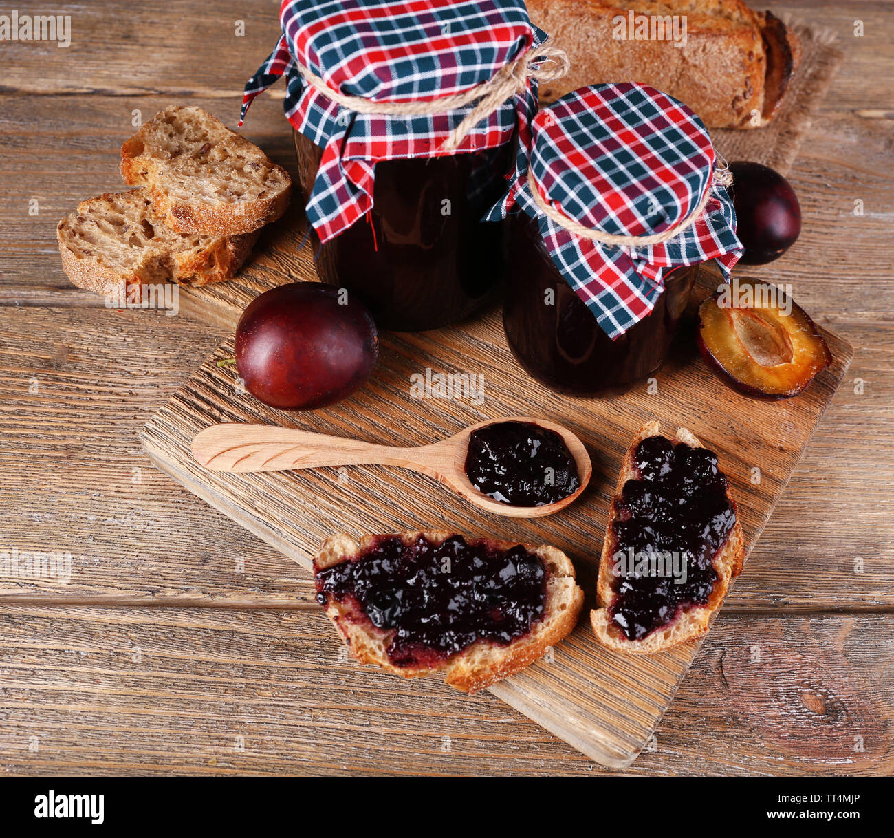 Tasty plum jam in jars and plums on wooden table Stock Photo - Alamy