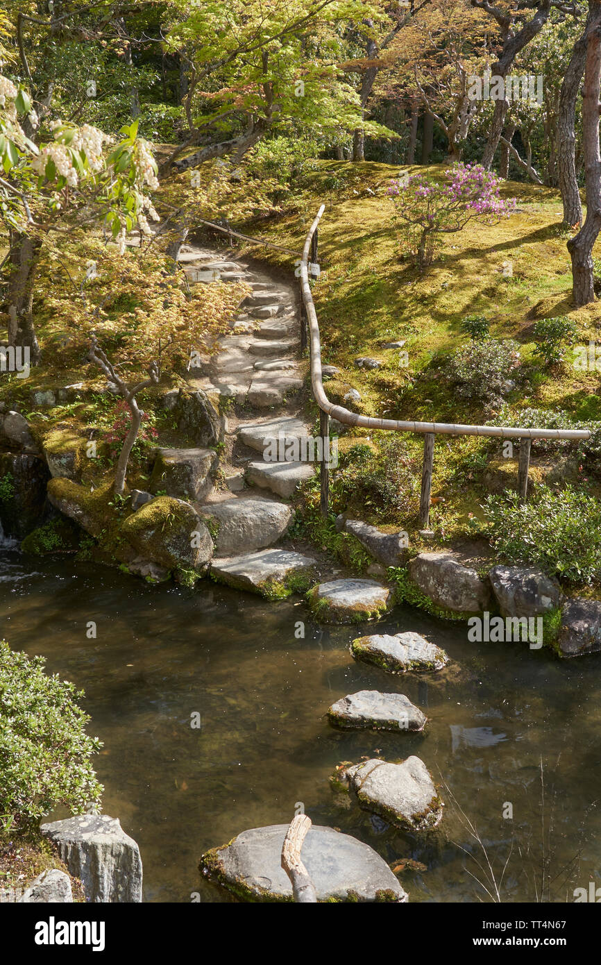 Japanese garden with a stone path across the river. The path then ...