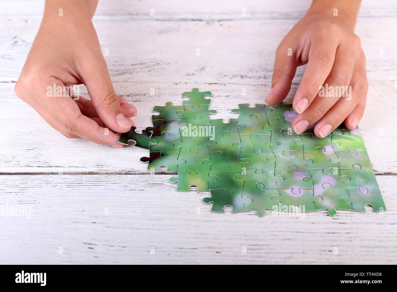 Hand holding puzzle piece on wooden table background Stock Photo - Alamy