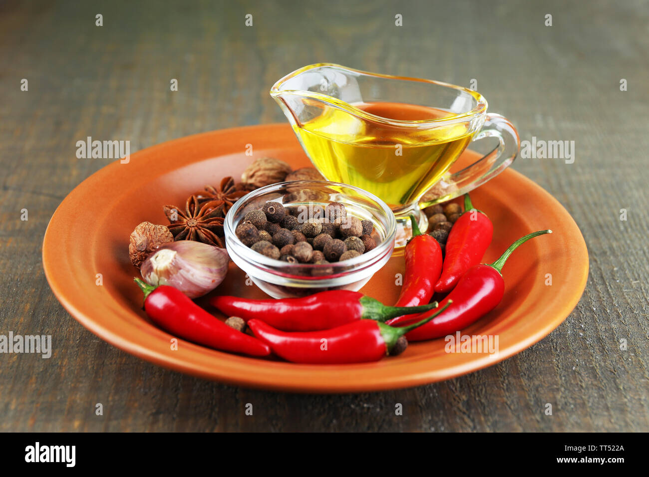 Set of spices and olive oil on plate, on wooden background Stock Photo ...
