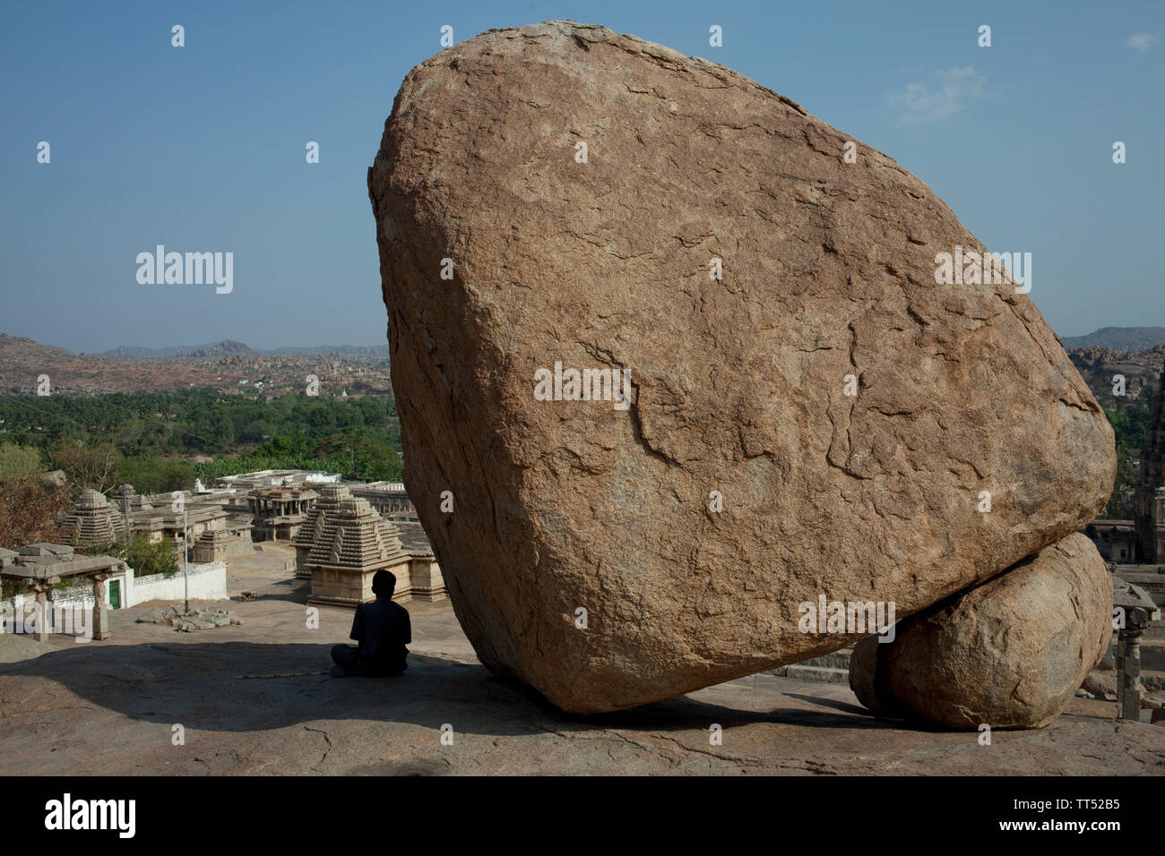 Man sheltering from the sun under a large boulder balanced on a ...