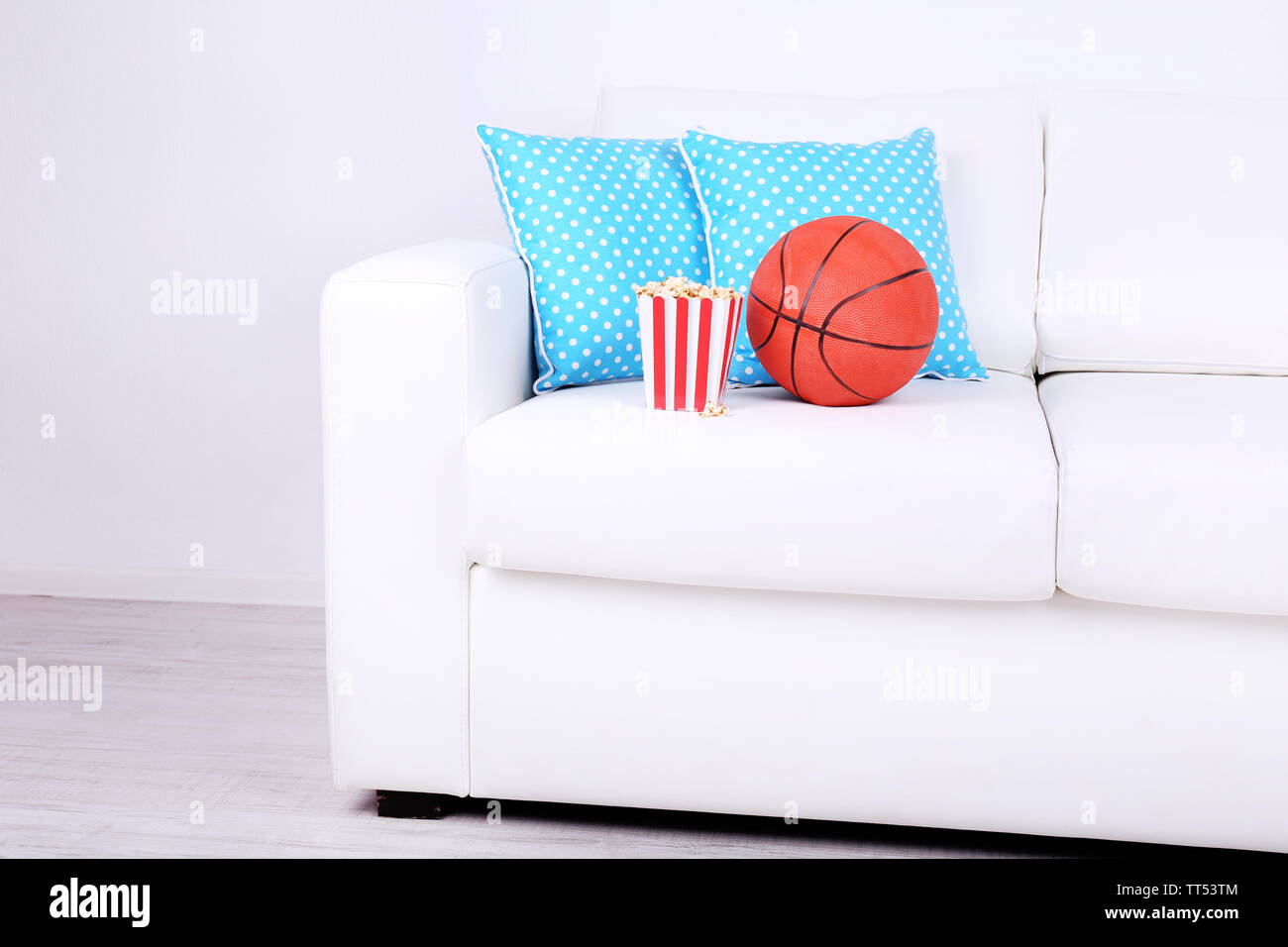 Popcorn and basketball on sofa in room Stock Photo - Alamy