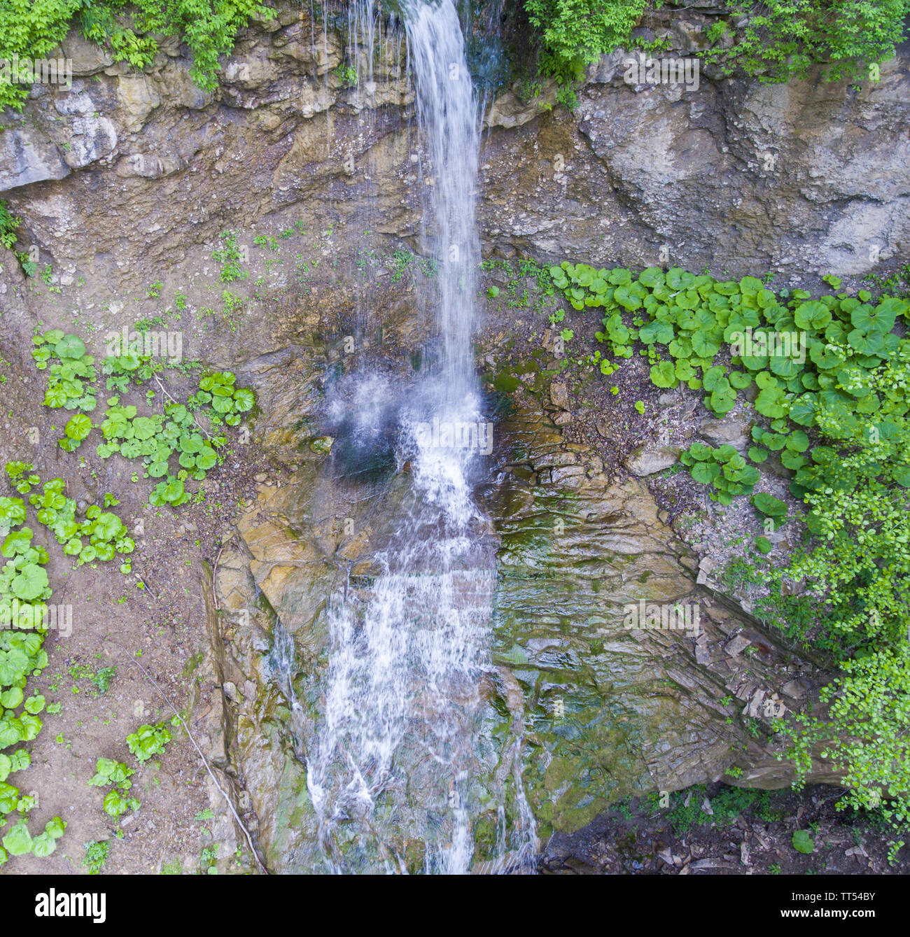 Long the flow of the waterfall cascading from the cliff. Aerial view ...