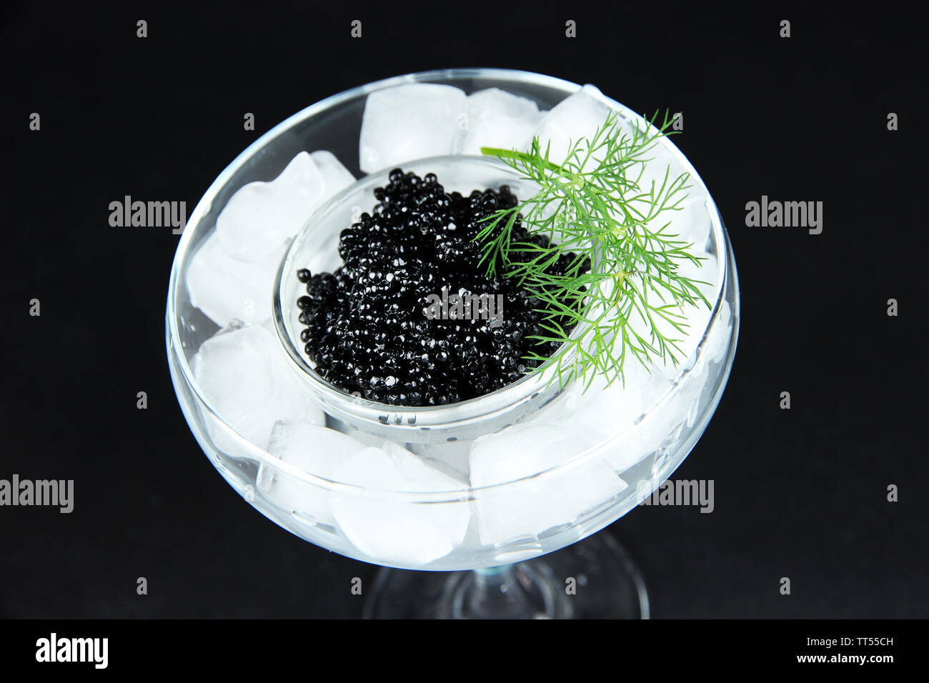 Glass bowl of black caviar and ice in goblet on dark background Stock ...