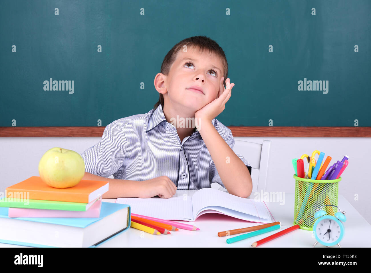 Schoolboy sitting in classroom on blackboard background Stock Photo - Alamy