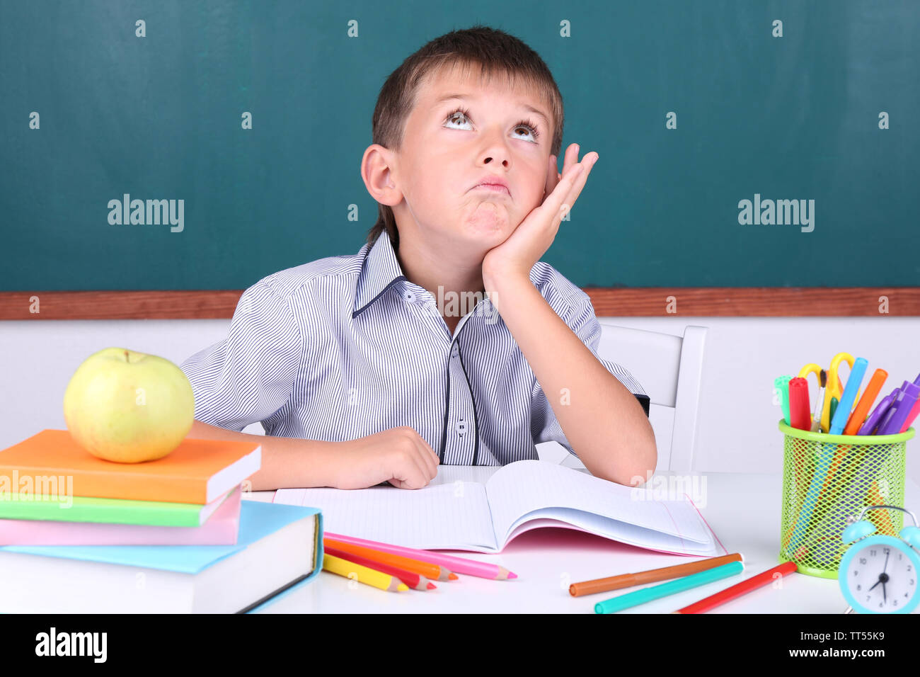 Schoolboy sitting in classroom on blackboard background Stock Photo - Alamy