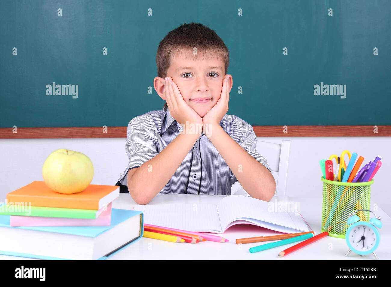 Schoolboy sitting in classroom on blackboard background Stock Photo - Alamy