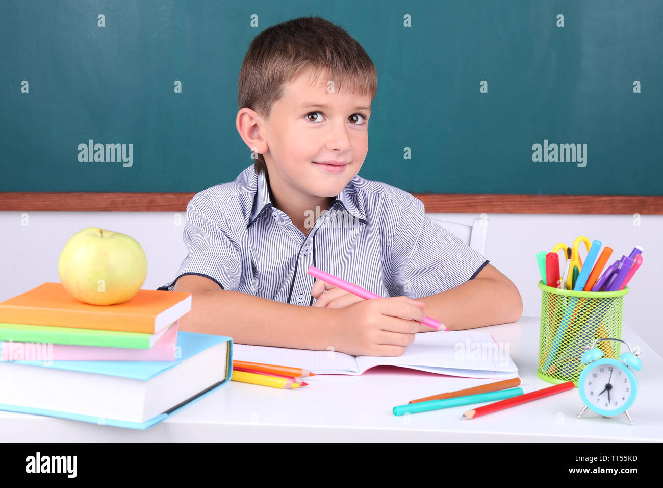 Schoolboy sitting in classroom on blackboard background Stock Photo - Alamy