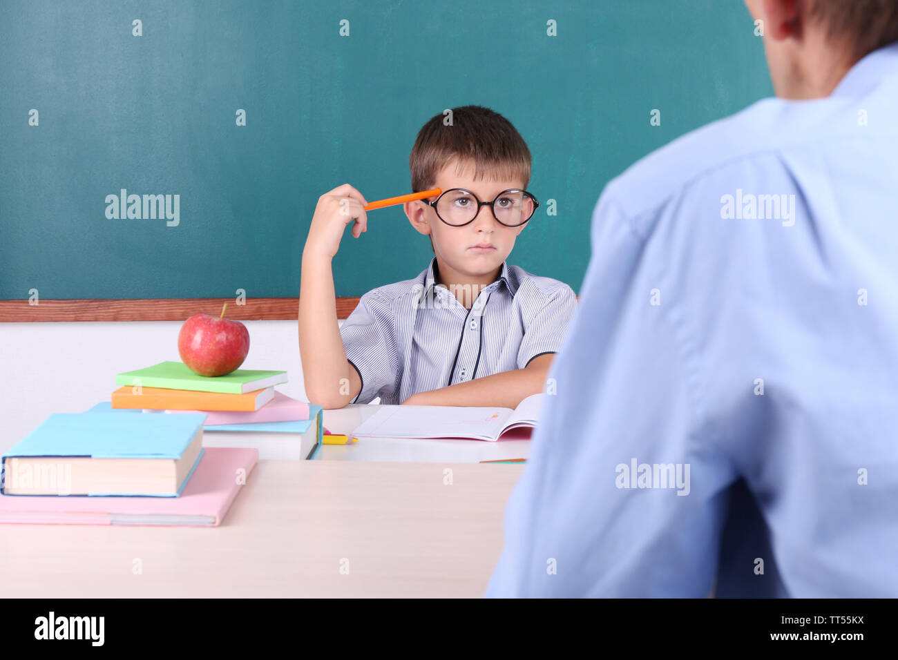 Schoolboy and teacher sitting in classroom on blackboard background ...