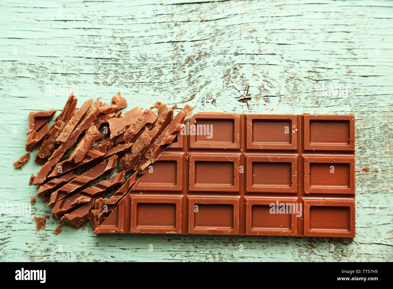 Milk chocolate bar on color wooden background Stock Photo - Alamy