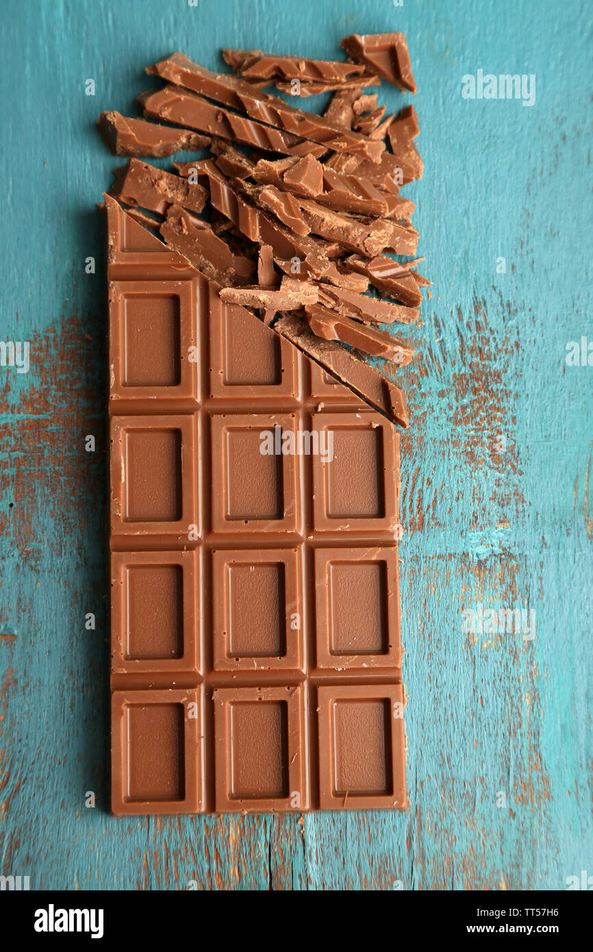 Milk chocolate bar on color wooden background Stock Photo - Alamy