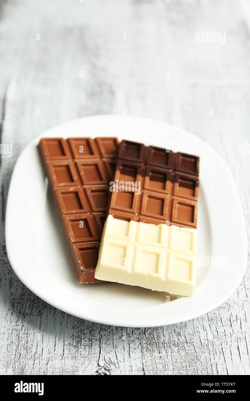 Chocolate bars on plate on wooden background Stock Photo - Alamy
