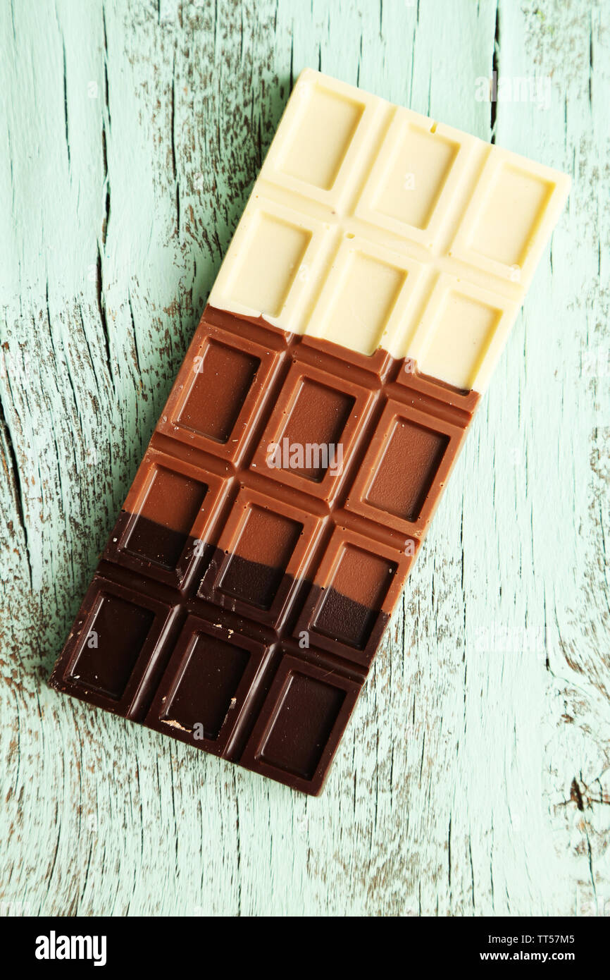 Milk chocolate bar on color wooden background Stock Photo - Alamy
