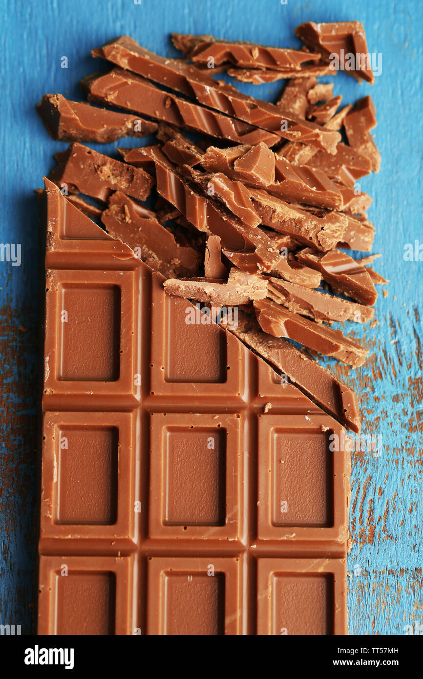 Milk chocolate bar on color wooden background Stock Photo - Alamy