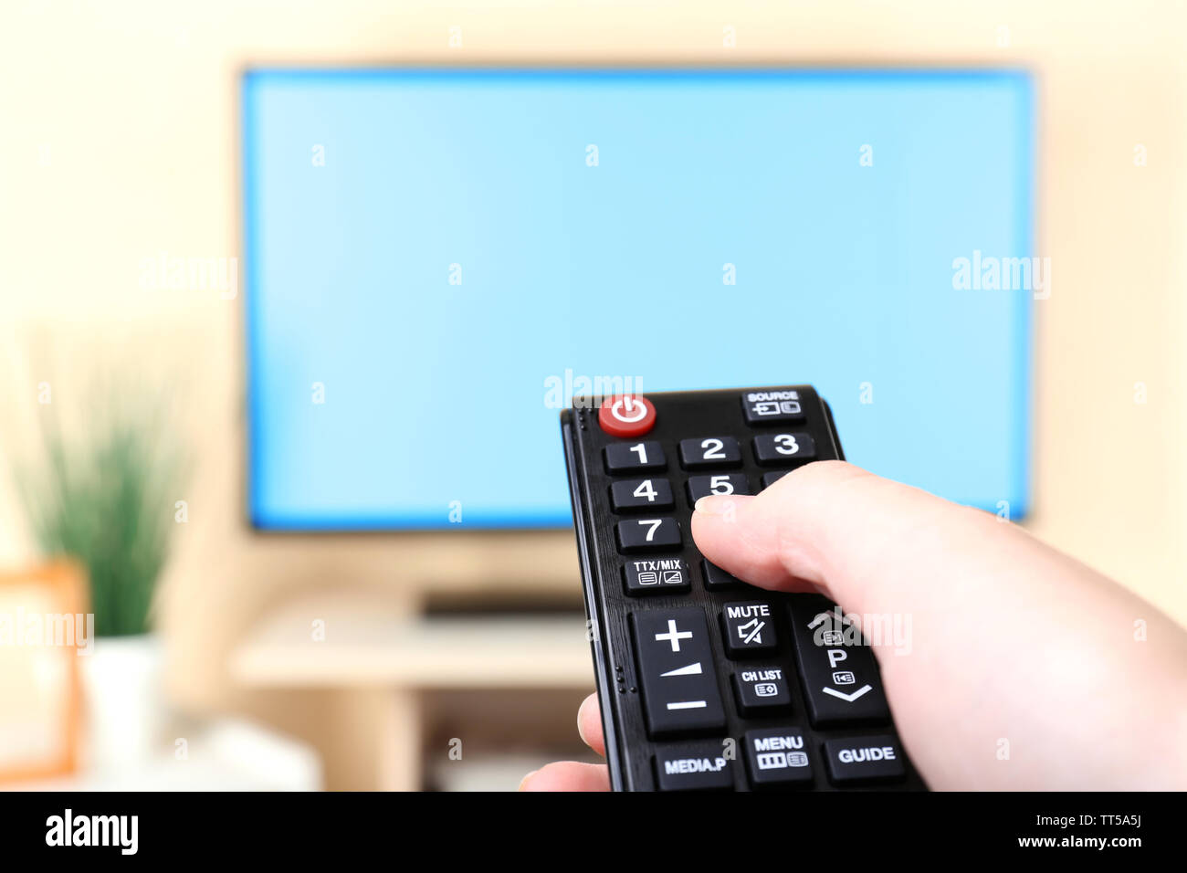 Watching TV and using remote controller Stock Photo - Alamy