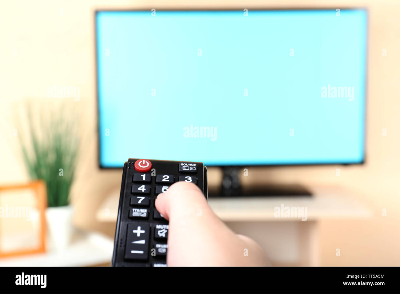 Watching TV and using remote controller Stock Photo - Alamy