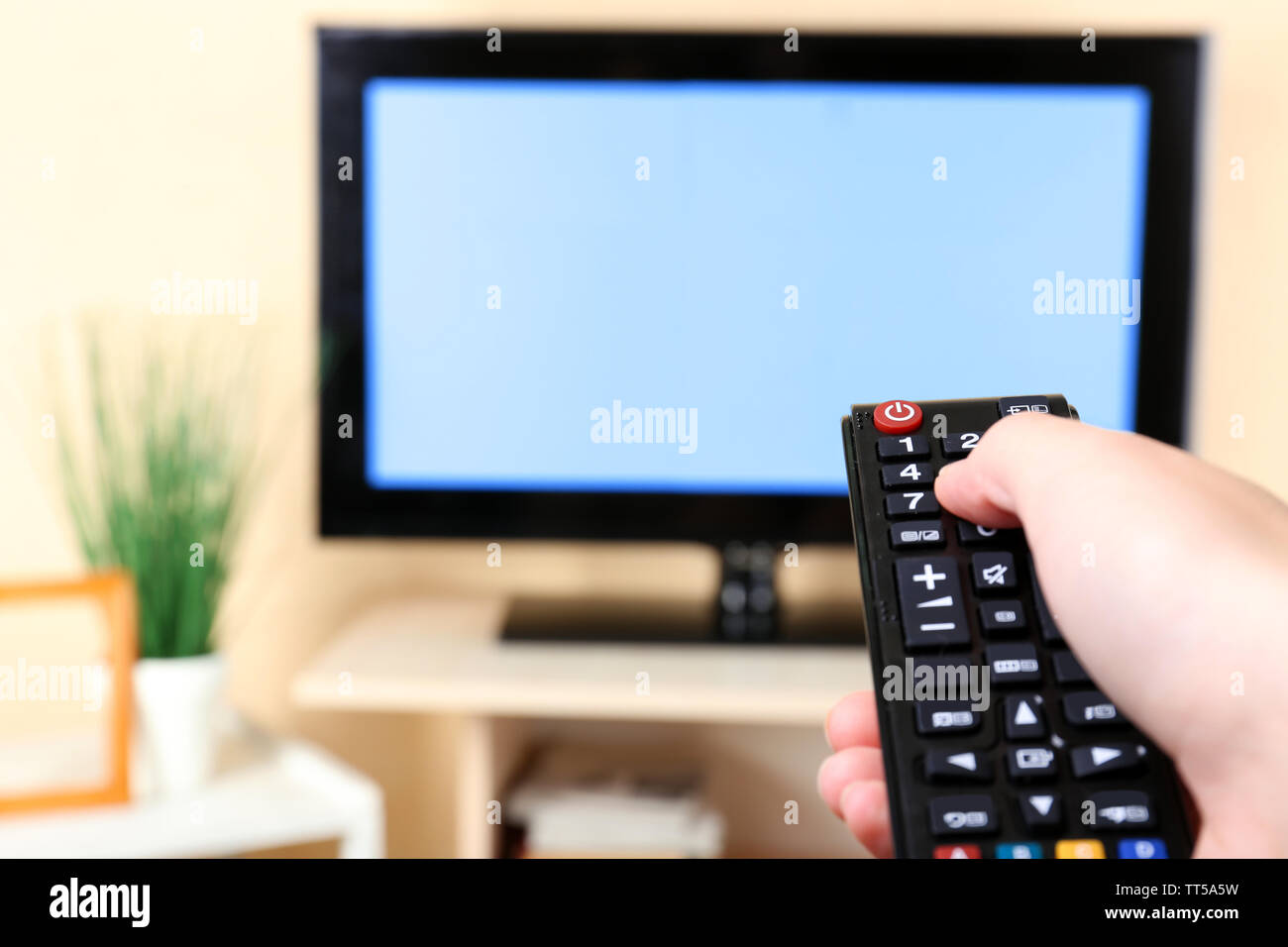 Watching TV and using remote controller Stock Photo - Alamy