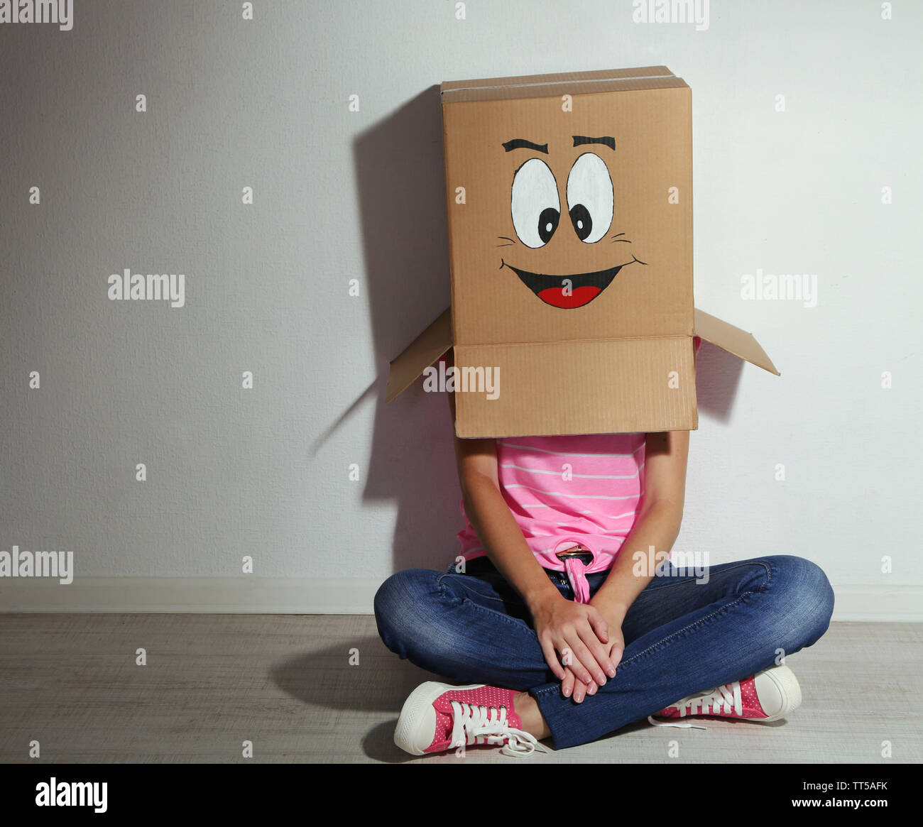 Woman with cardboard box on her head with happy face near wall Stock ...