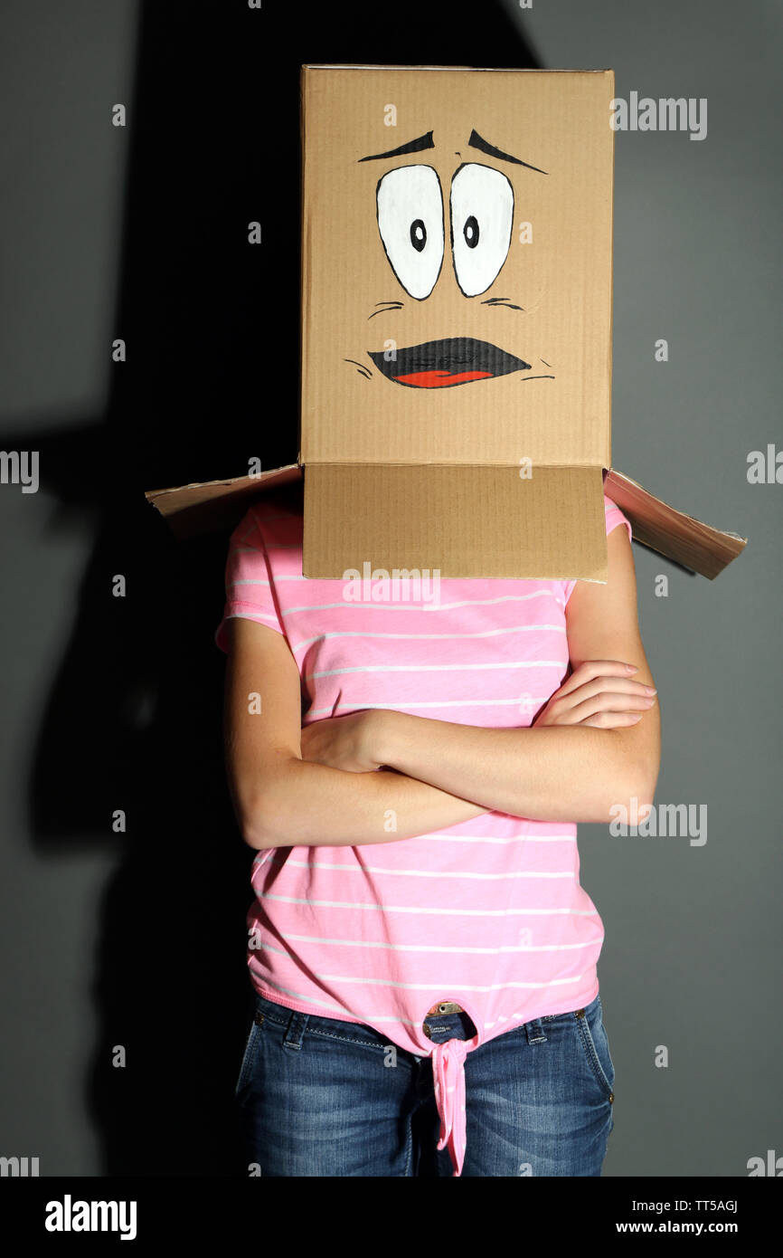 Woman with cardboard box on her head with sad face, on grey background ...