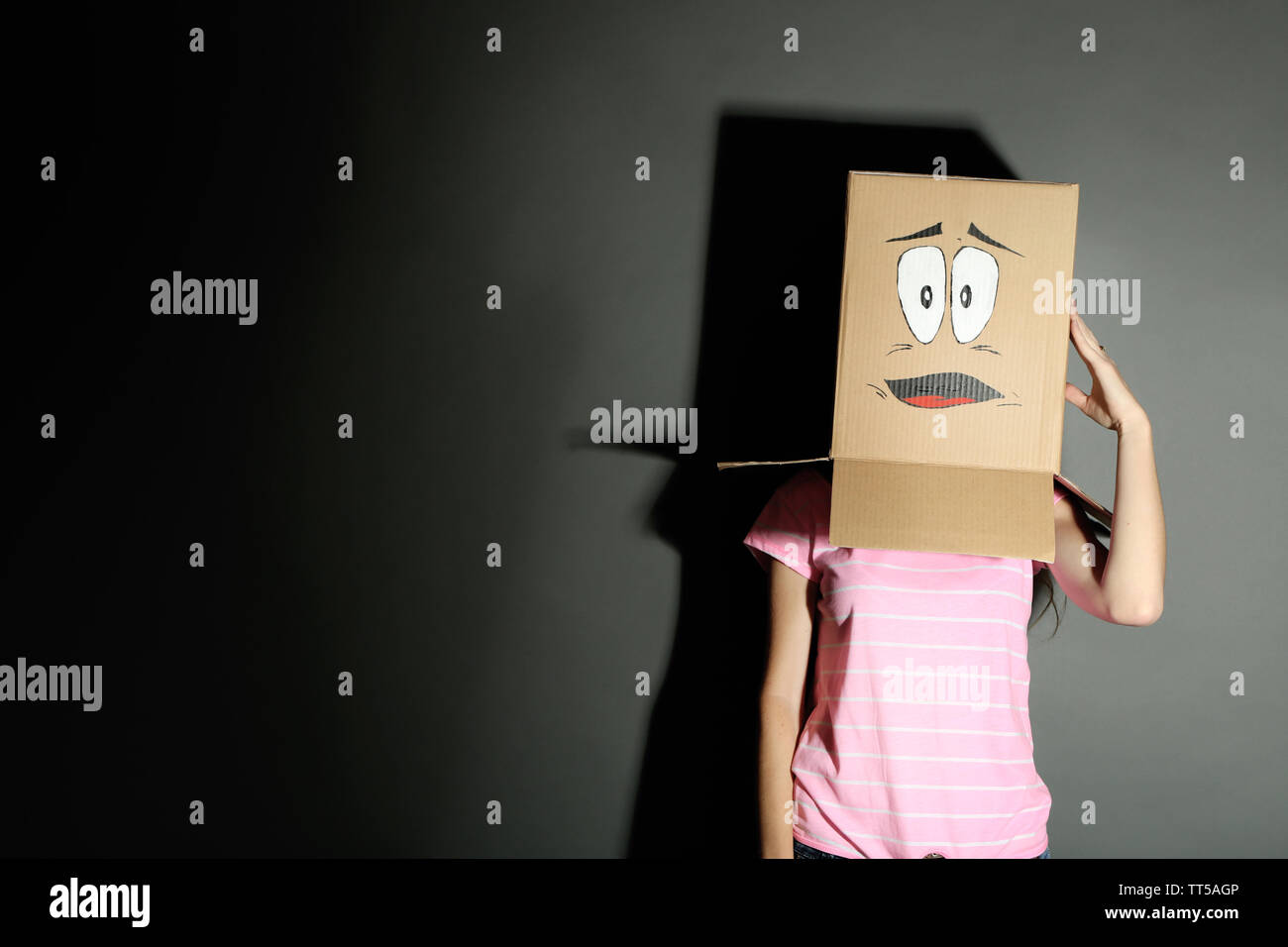 Woman with cardboard box on her head with sad face, on grey background ...