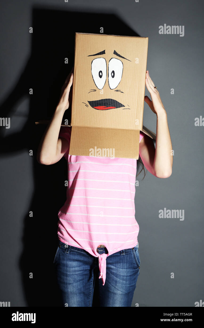 Woman with cardboard box on her head with sad face, on grey background ...
