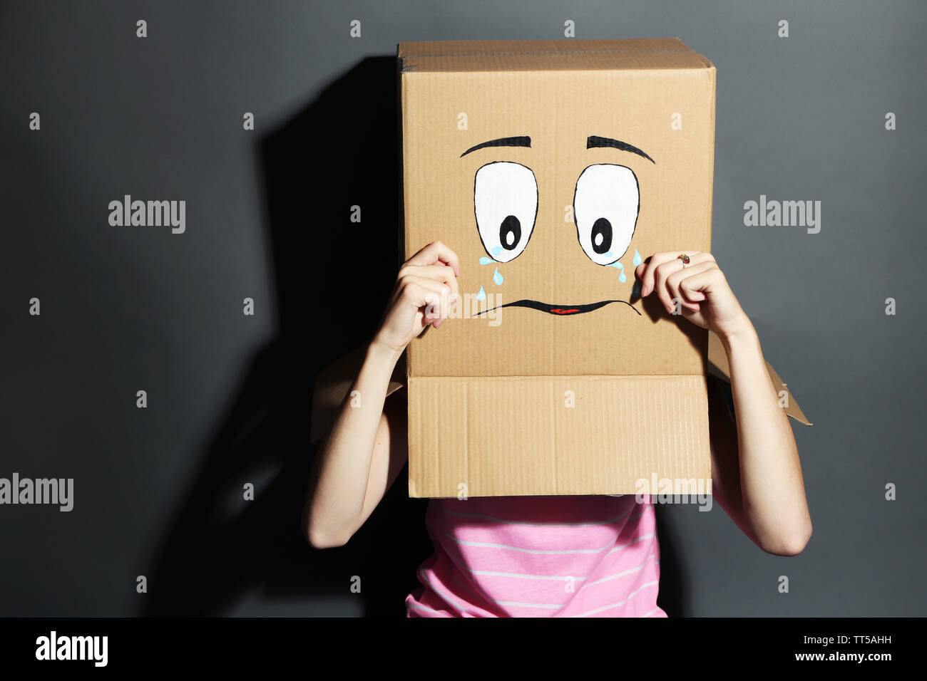 Woman with cardboard box on her head with sad face, on grey background ...