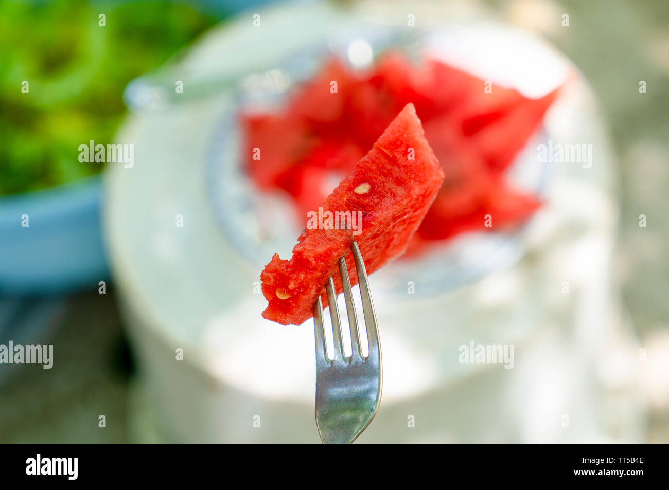 Slice of red watermelon on a fork and watermelon slices in bowl on ...