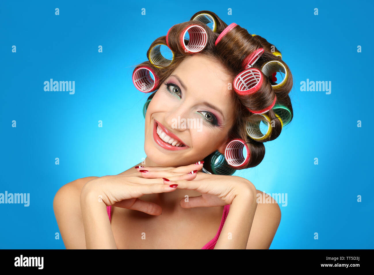 Beautiful girl in hair curlers on blue background Stock Photo - Alamy